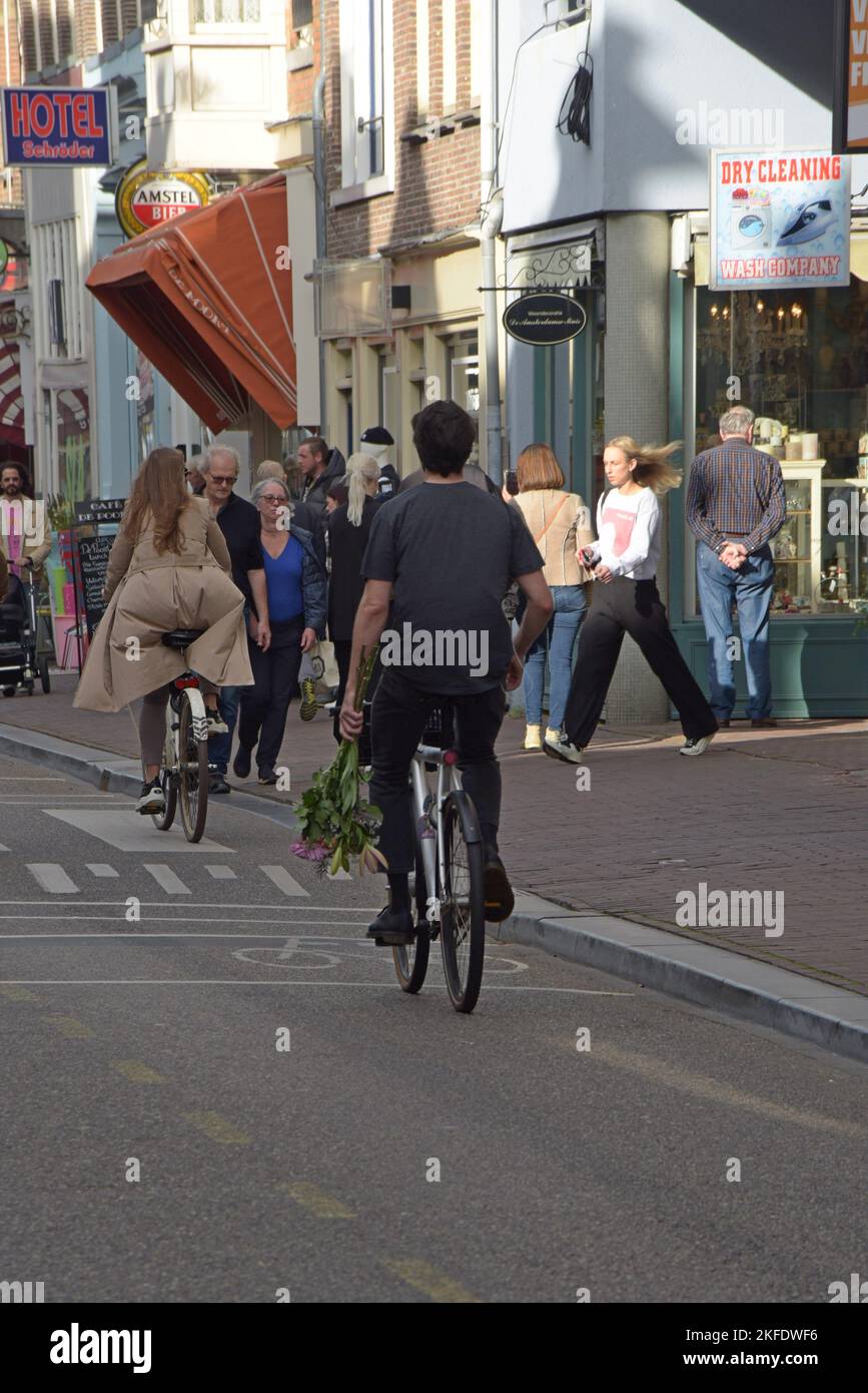 A Dutch man cycling one handed carrying a bunch of flowers on a bicycle ...