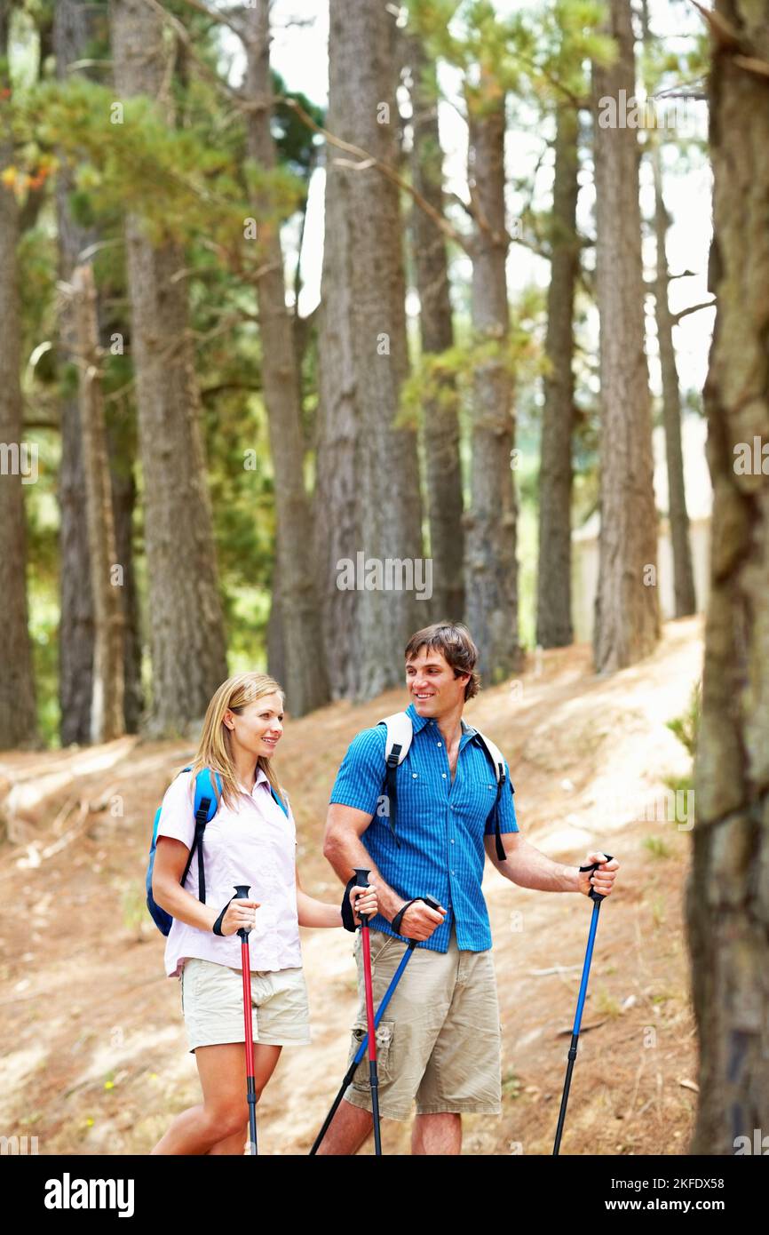 Trekking. Happy couple walking with backpack and trekking poles while ...