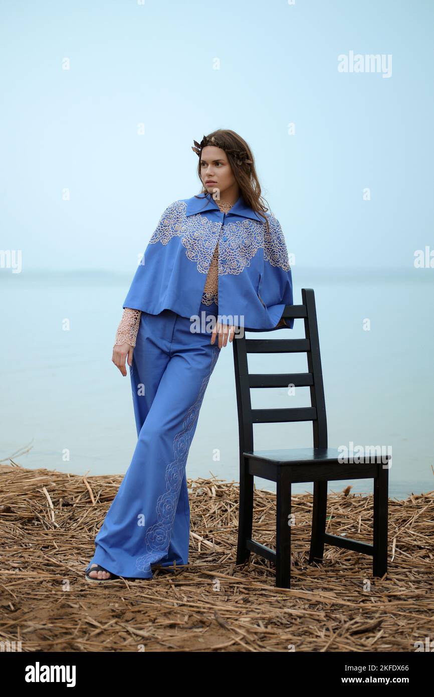Calm lonely woman leaning against a chair in a cloudy day on a beach ...