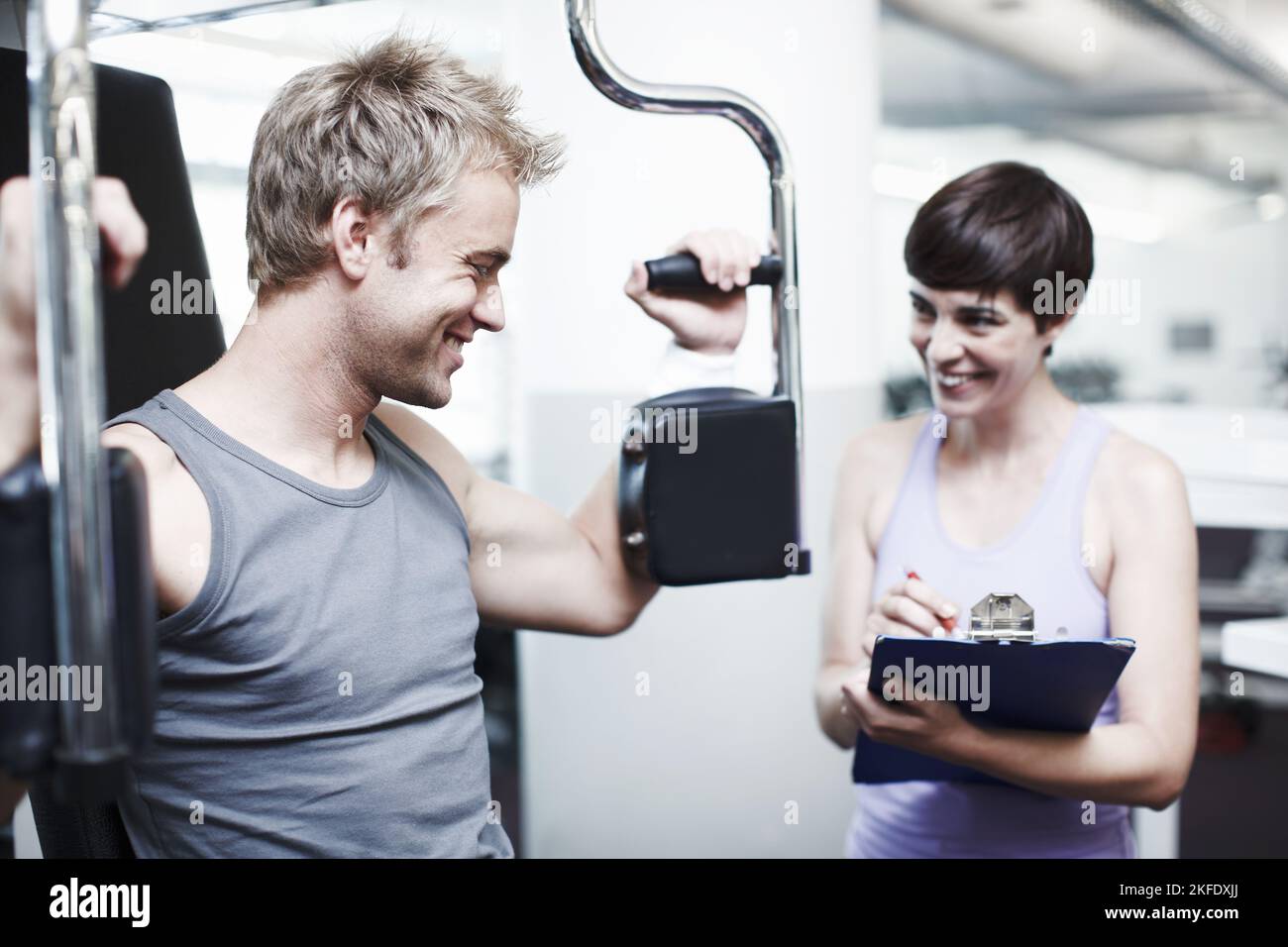 How am I doing, coach. a handsome young man using an exercise machine ...