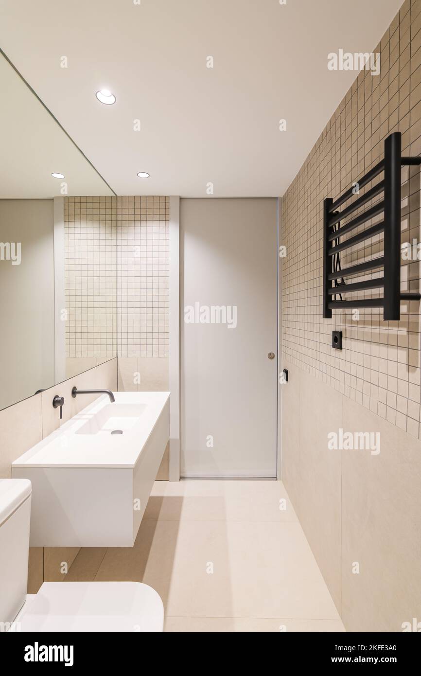 Vertical view of interior of modern bathroom with beige tiles, black ...
