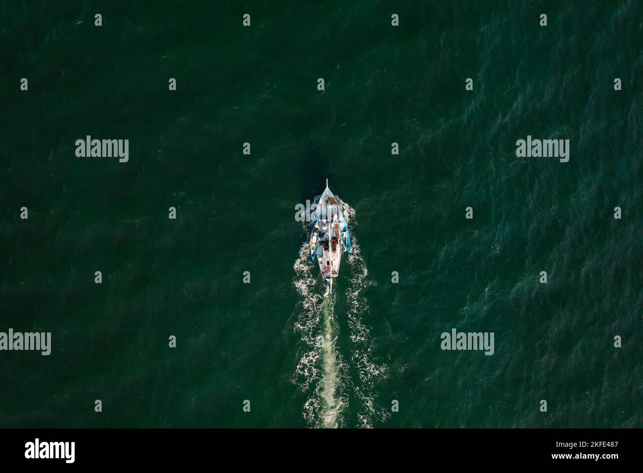 An aerial shot of fishermen on boats sailing in the ocean and leaving ...