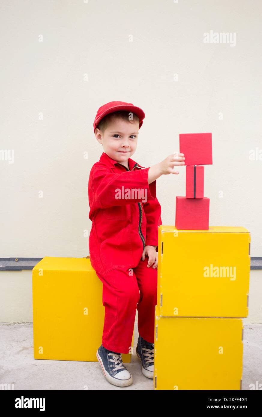 Toddler boy in red overalls - uniform and cap stacks one on one ...