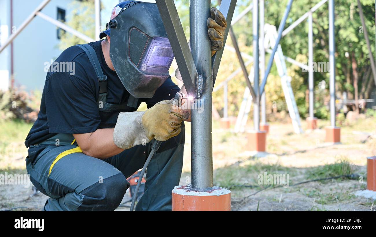 Welder welding metal beam with welding machine for installing solar ...