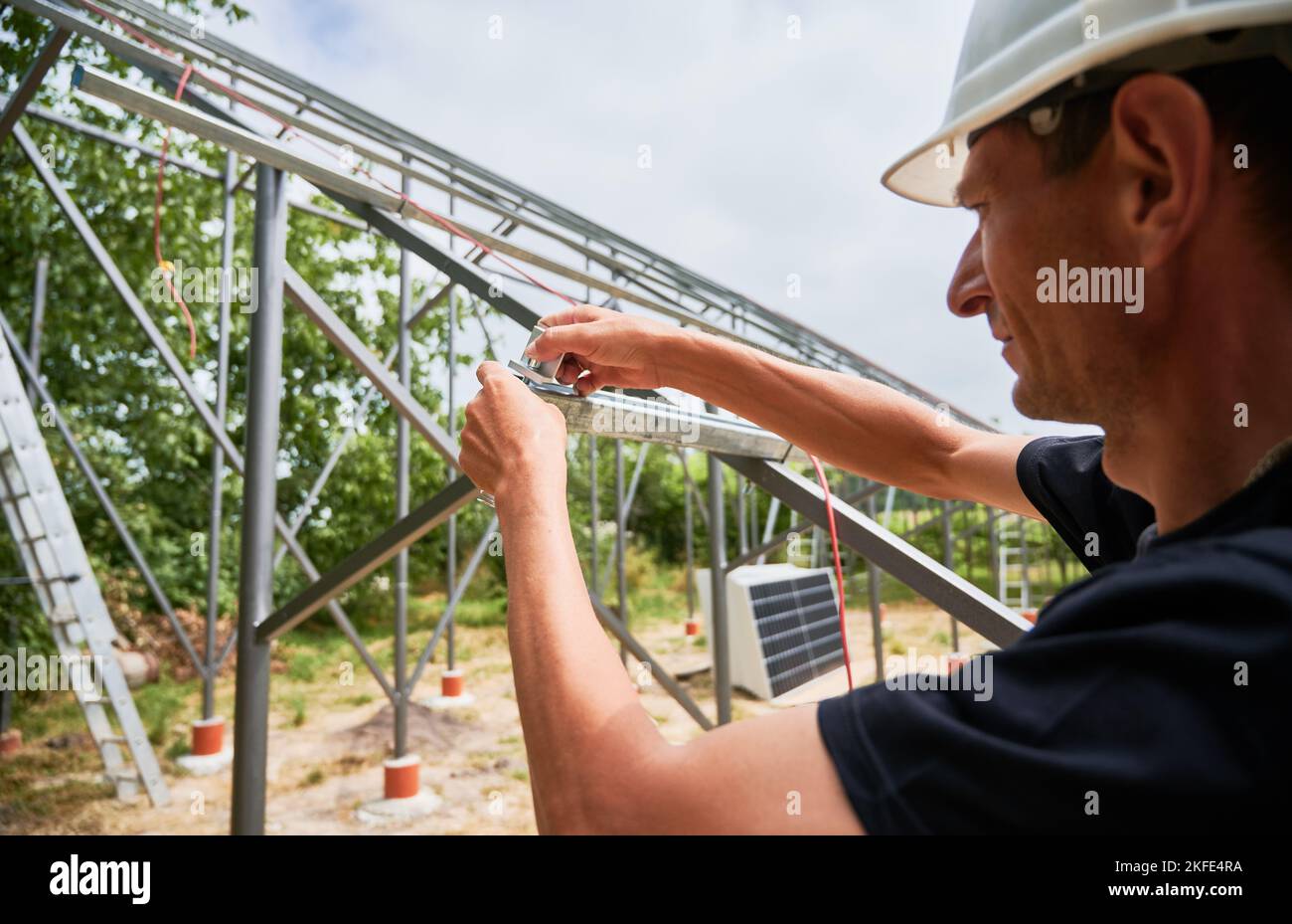 Worker tightening mounting clamp in metal beam for installing solar ...