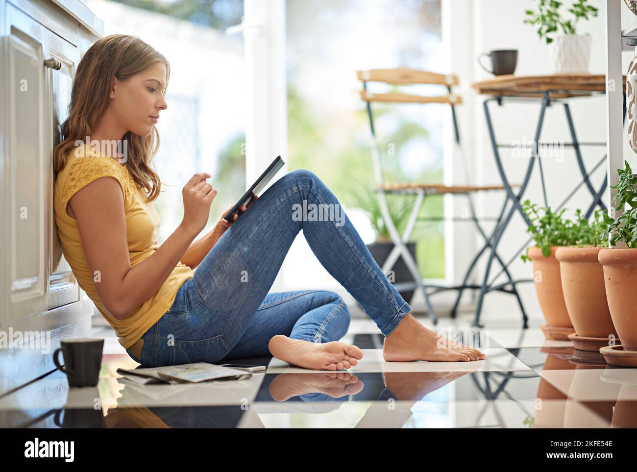 Relaxing in the kitchen. an attractive young woman chilling on her ...