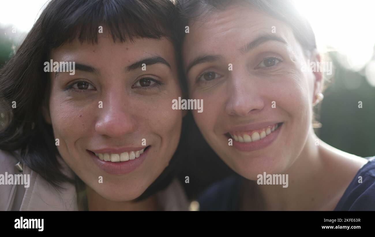Two young women faces together cheek to cheek. Portrait of diverse ...