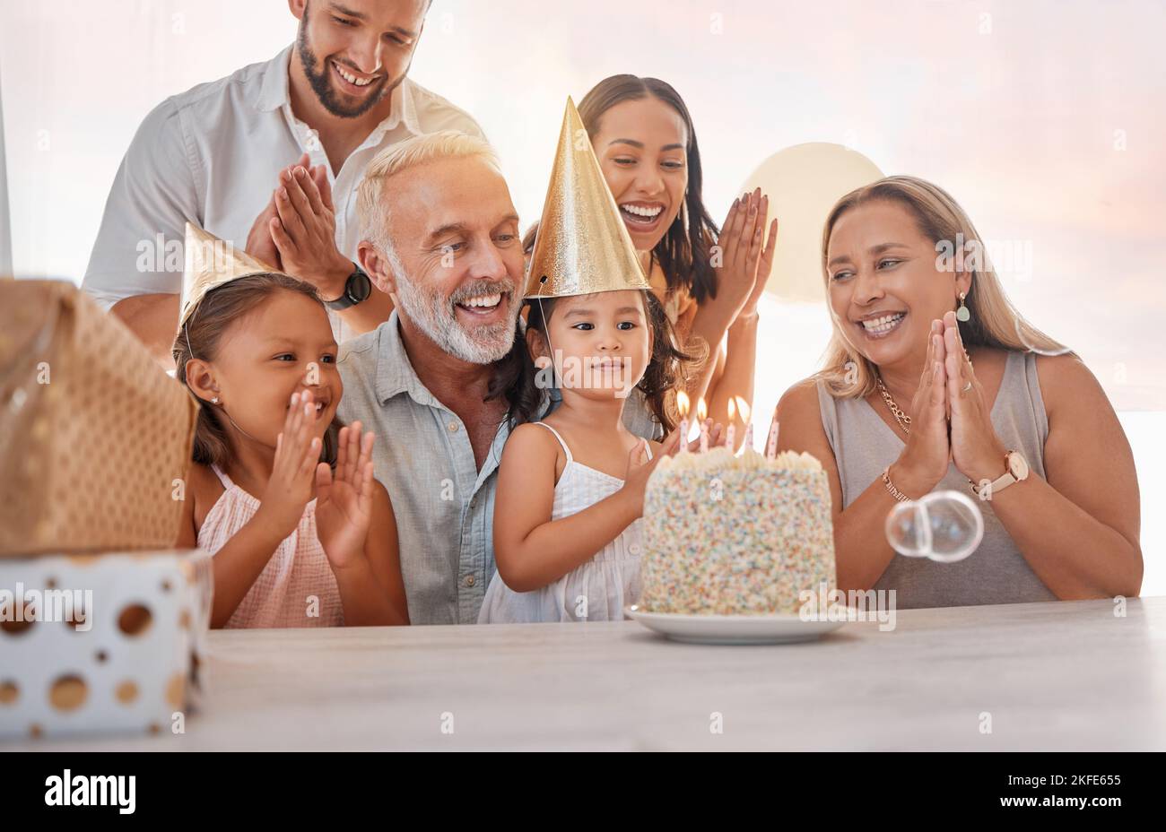 Family, birthday party and cake with celebration, clapping and singing ...