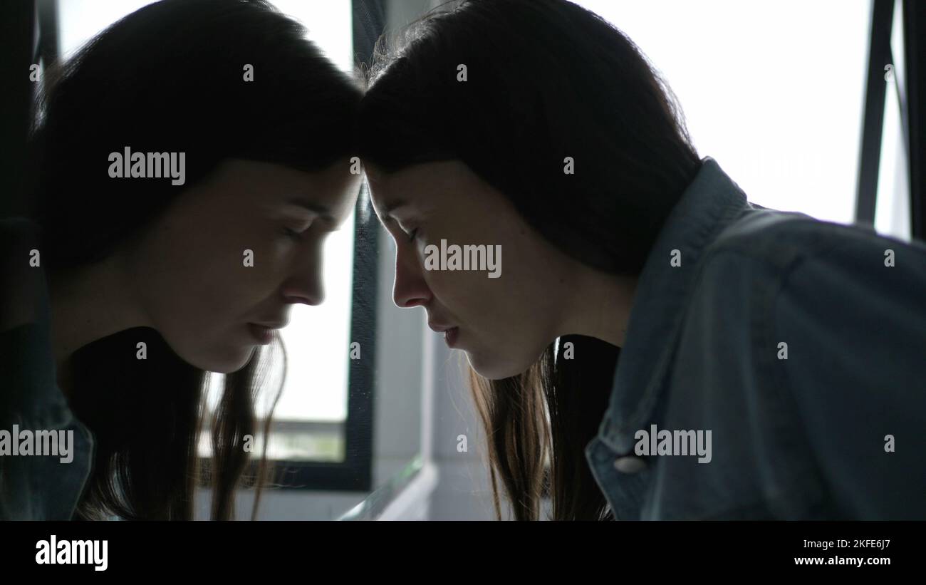 Anxious woman looking at her own reflection at bathroom mirror feeling ...