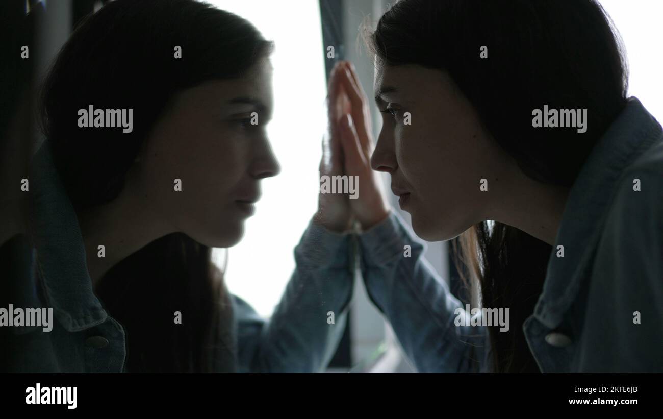 Anxious woman looking at her own reflection at bathroom mirror feeling ...