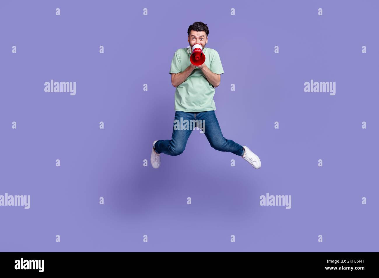 Full body photo of handsome young guy jumping screaming loudspeaker ...