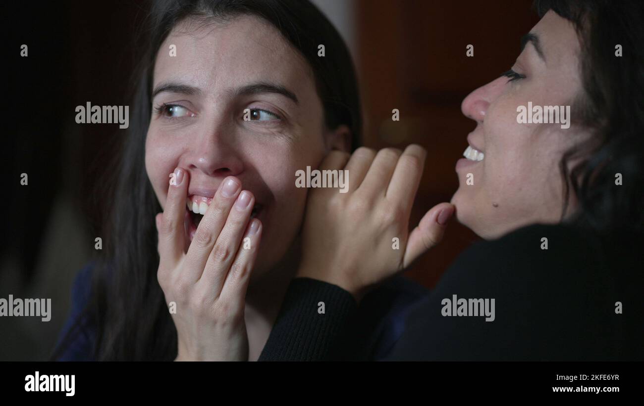 Friend telling secret to woman ear whispering. Young woman shock ...