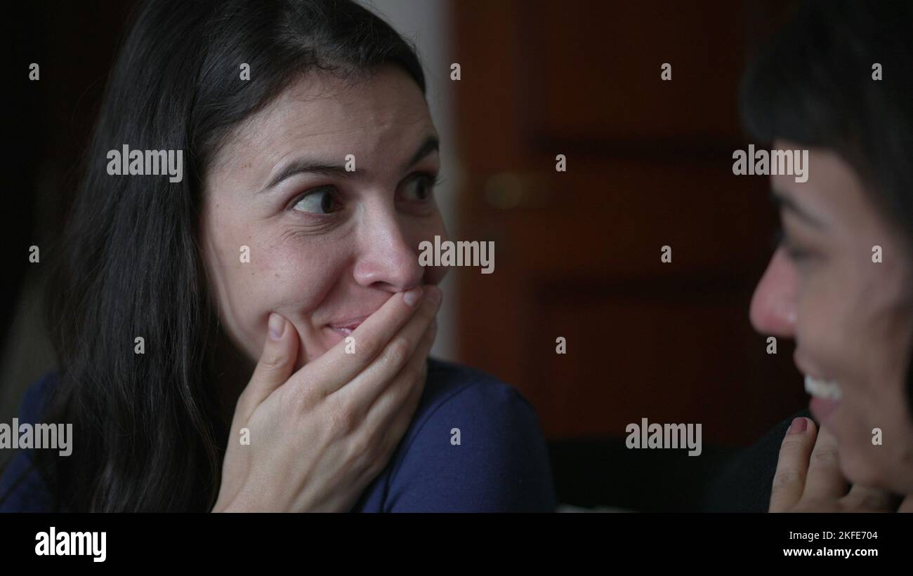 Friend telling secret to woman ear whispering. Young woman shock ...