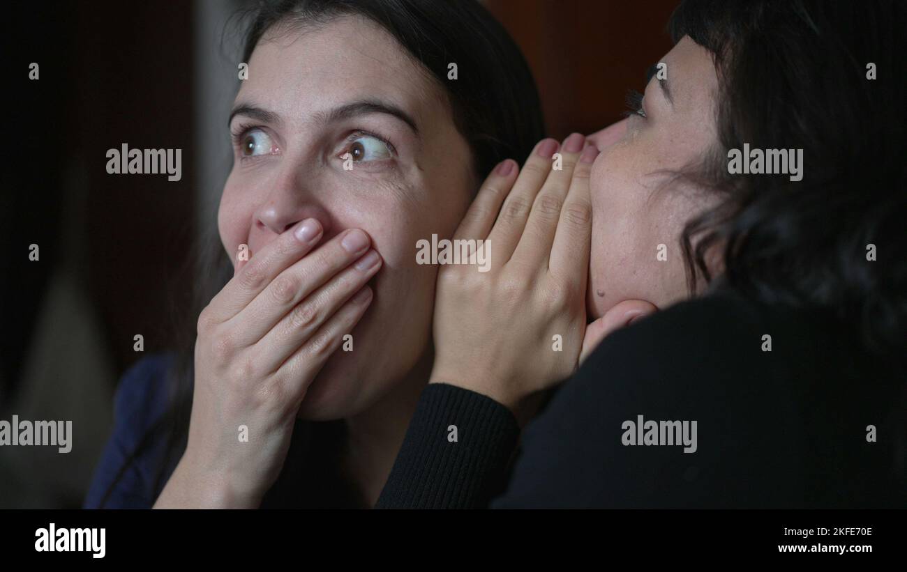 Friend telling secret to woman ear whispering. Young woman shock ...