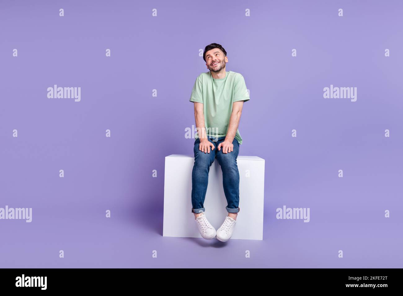 Full size photo of handsome young guy sit shy pose white cube look ...