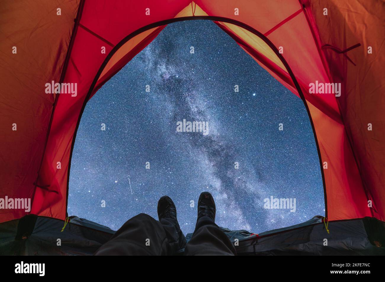 Hiker man relaxing inside a tent and milky way with starry in the night ...