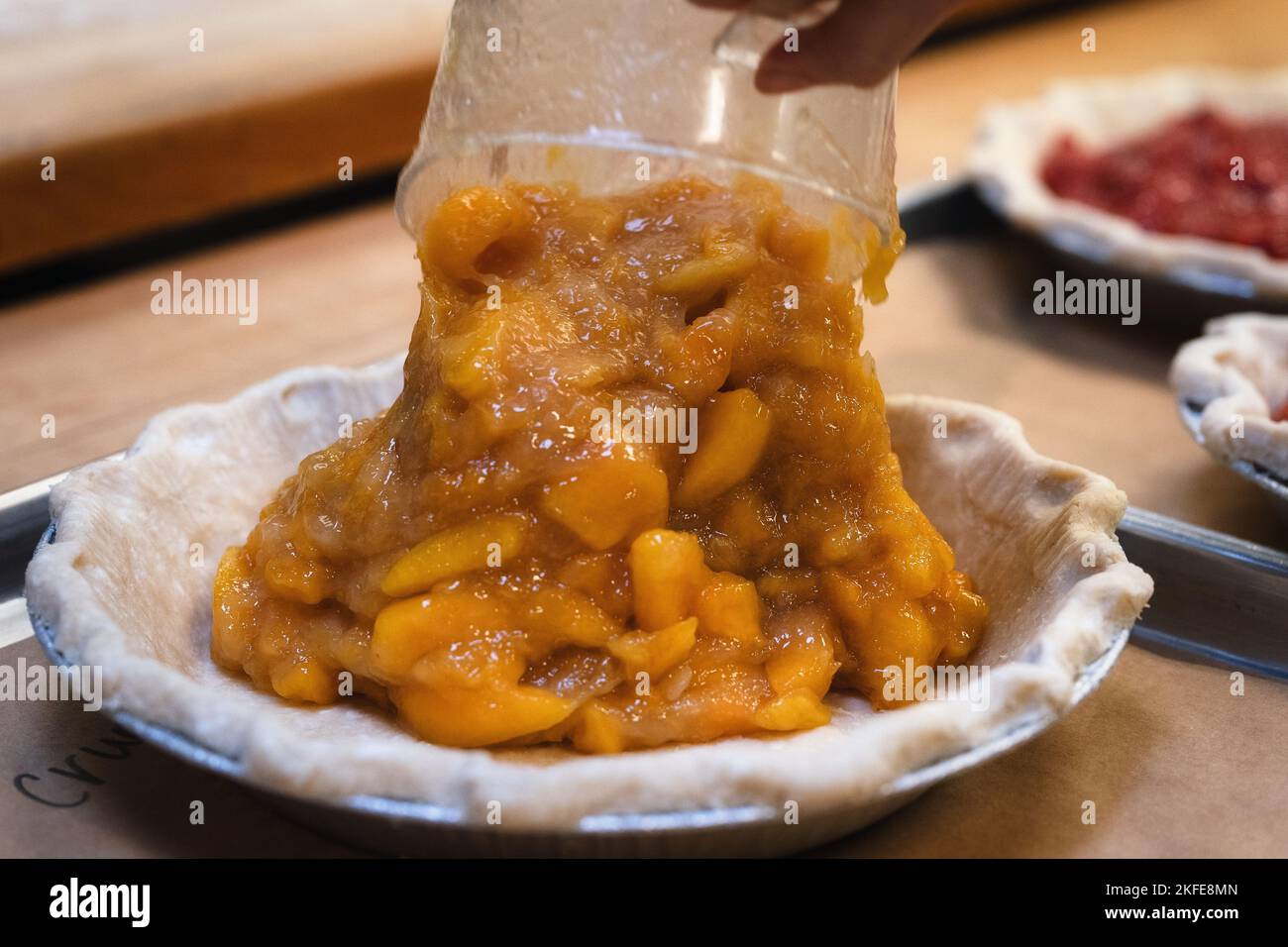 pouring peach filling into a pie shell Stock Photo - Alamy