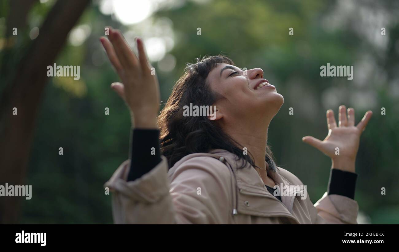 Religious thankful young woman raising arms in air celebrating life in ...