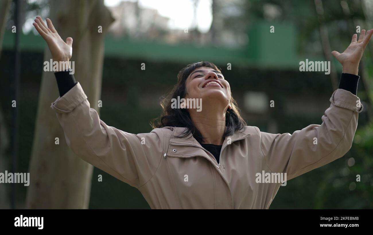 Religious thankful young woman raising arms in air celebrating life in ...