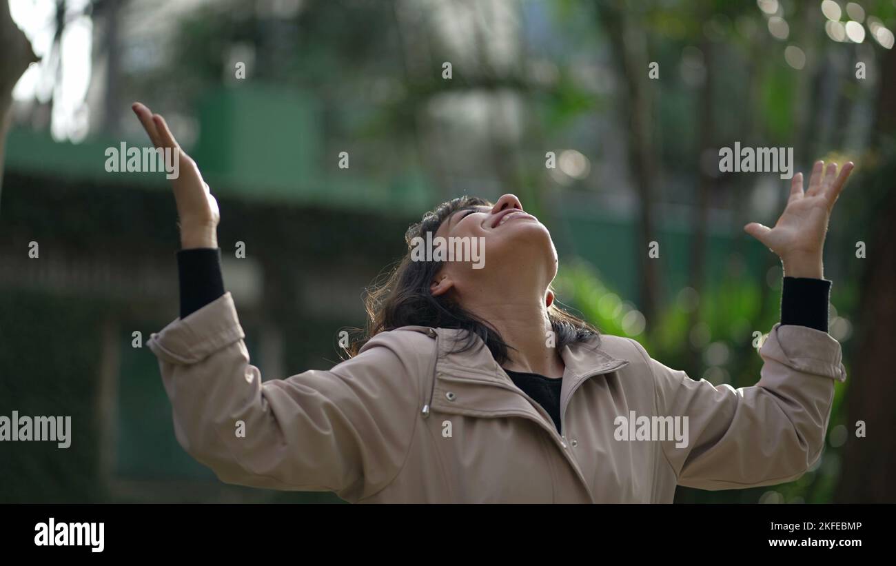 Religious thankful young woman raising arms in air celebrating life in ...