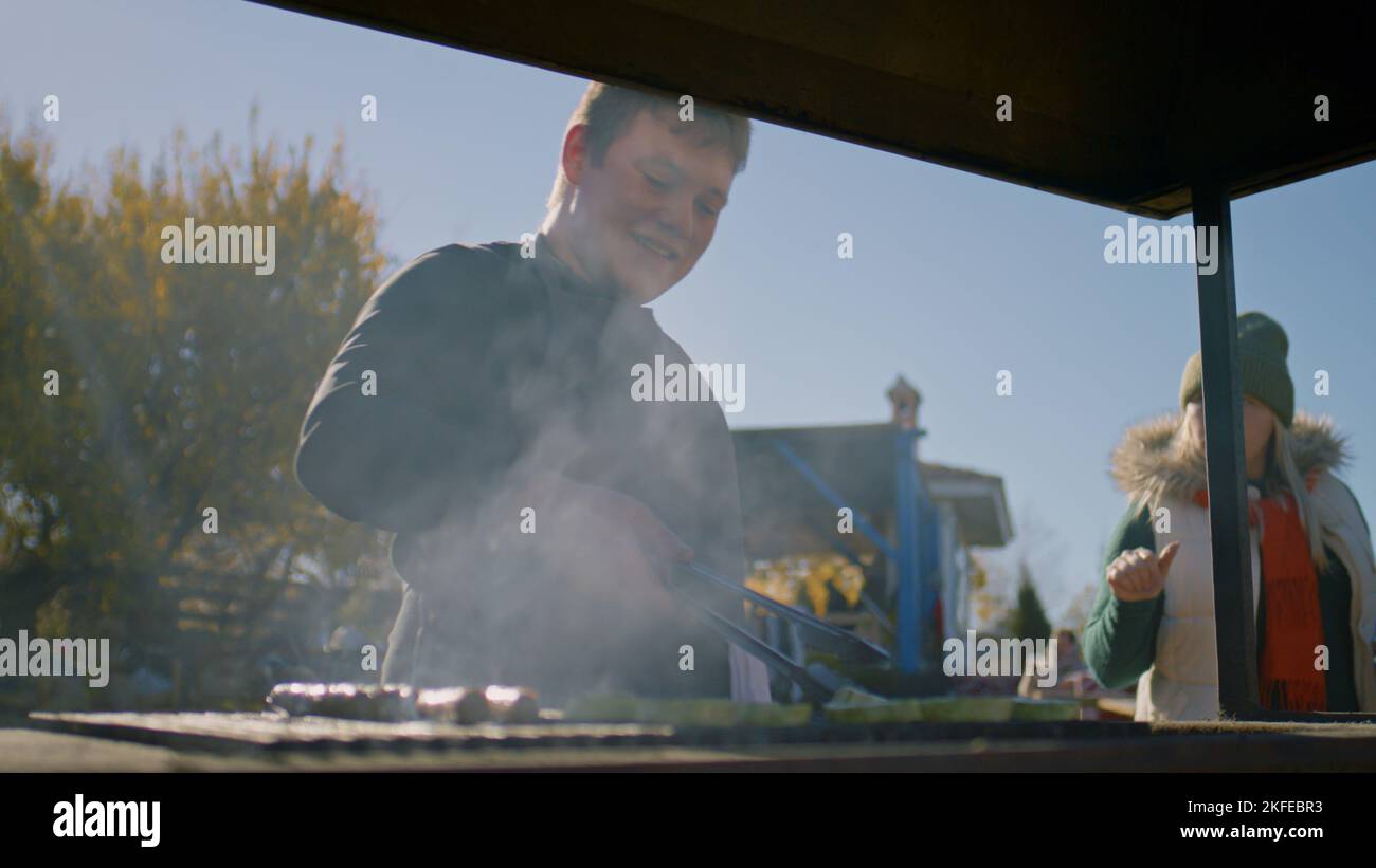 Adult man cooks on grill, turn over vegetables, shows way to point of ...