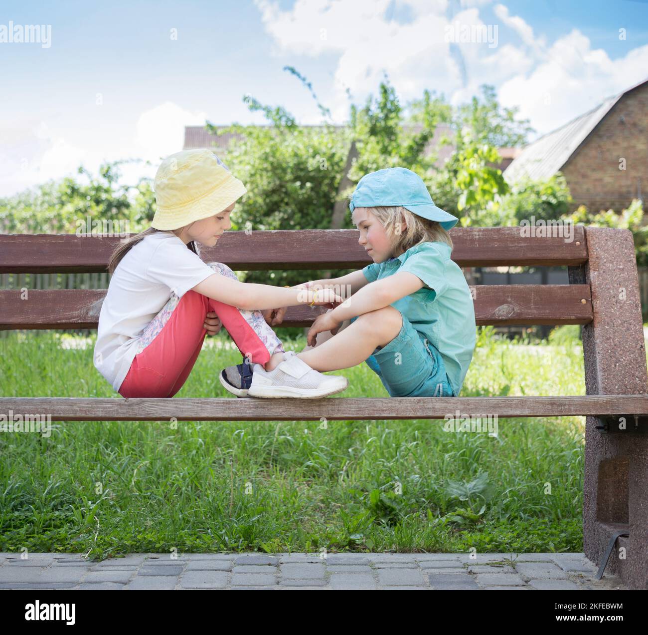 Two preschool children, girl and boy, are sitting on bench opposite ...