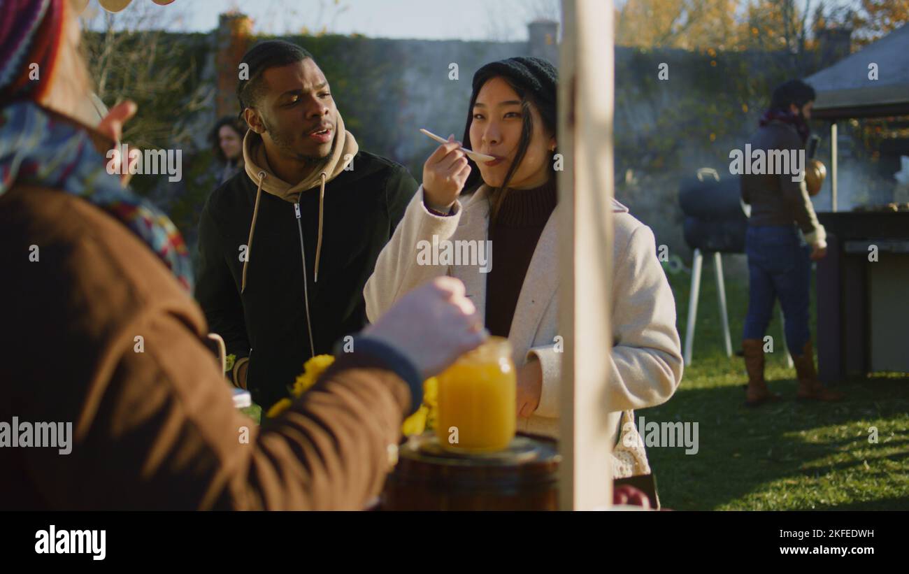 Diverse couple shopping at local farmers market. Asian woman tastes a ...