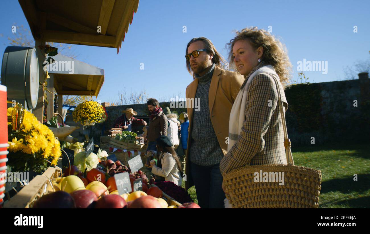 Adult couple standing at the stall with fruits and vegetables. People ...