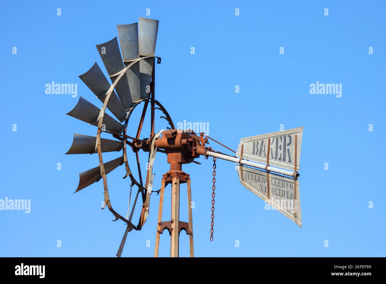A low-angle closeup of a broken windmill with the clear blue sky in the ...