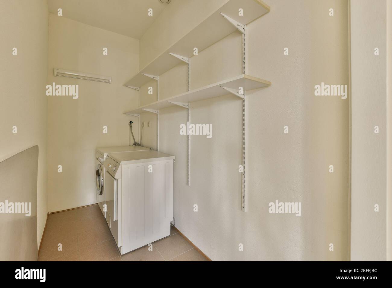 Interior of modern bright laundry room with white walls and tilet floor ...