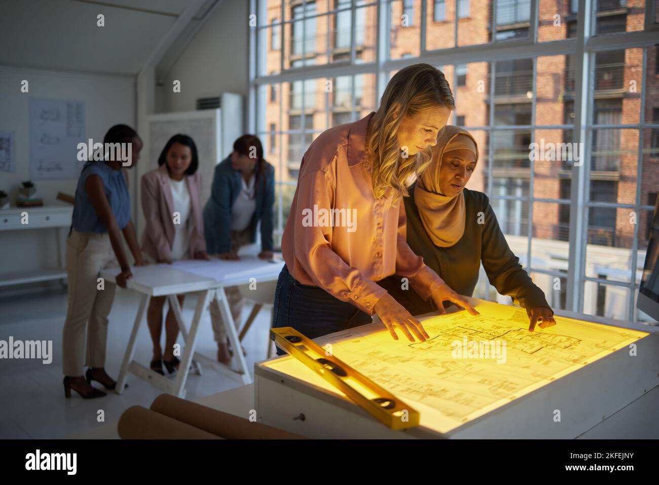 Architecture, blueprint and planning business women on light table or ...