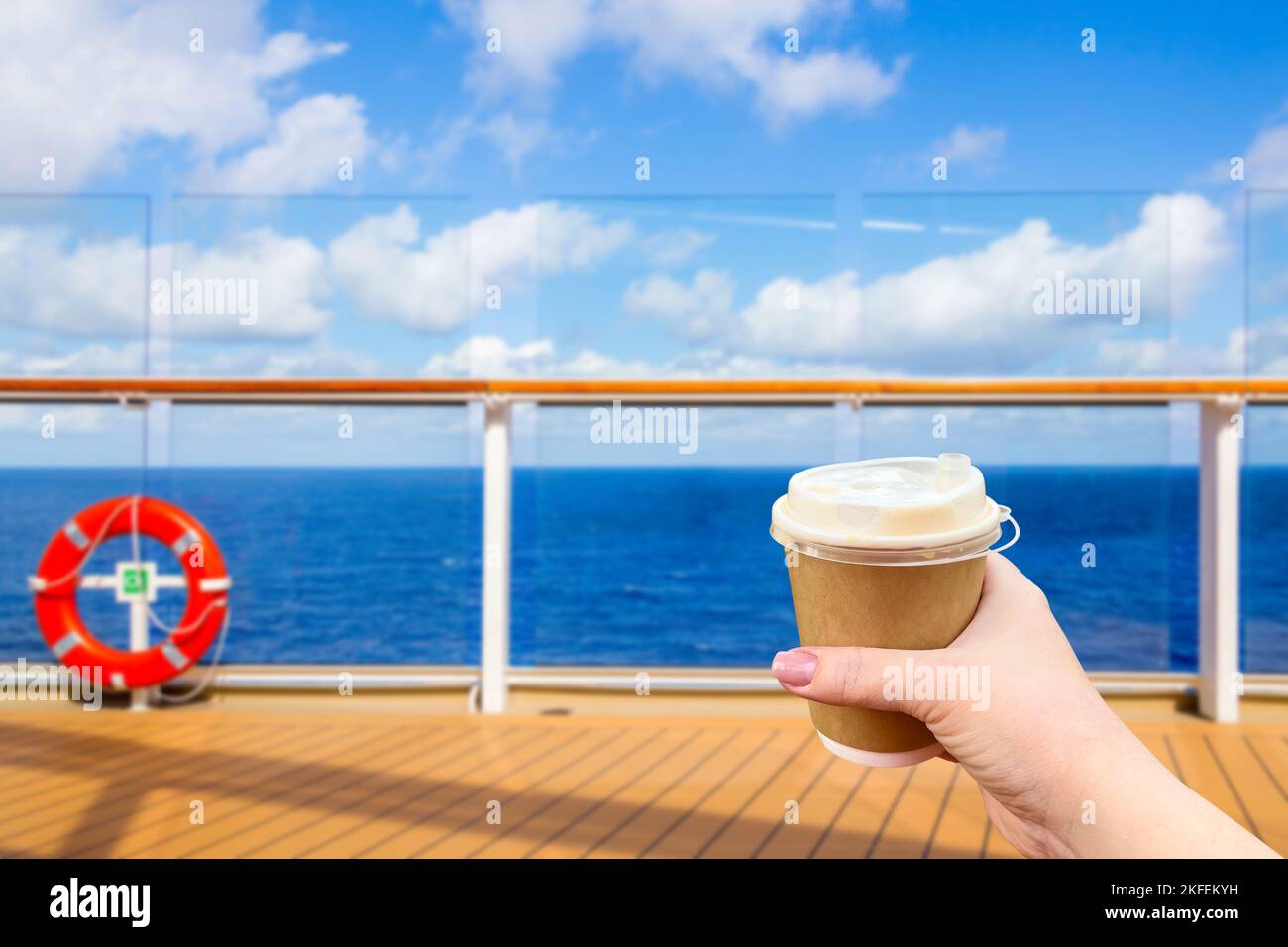 Hand holding paper cup of hot coffee on a deck of cruise ship with ...