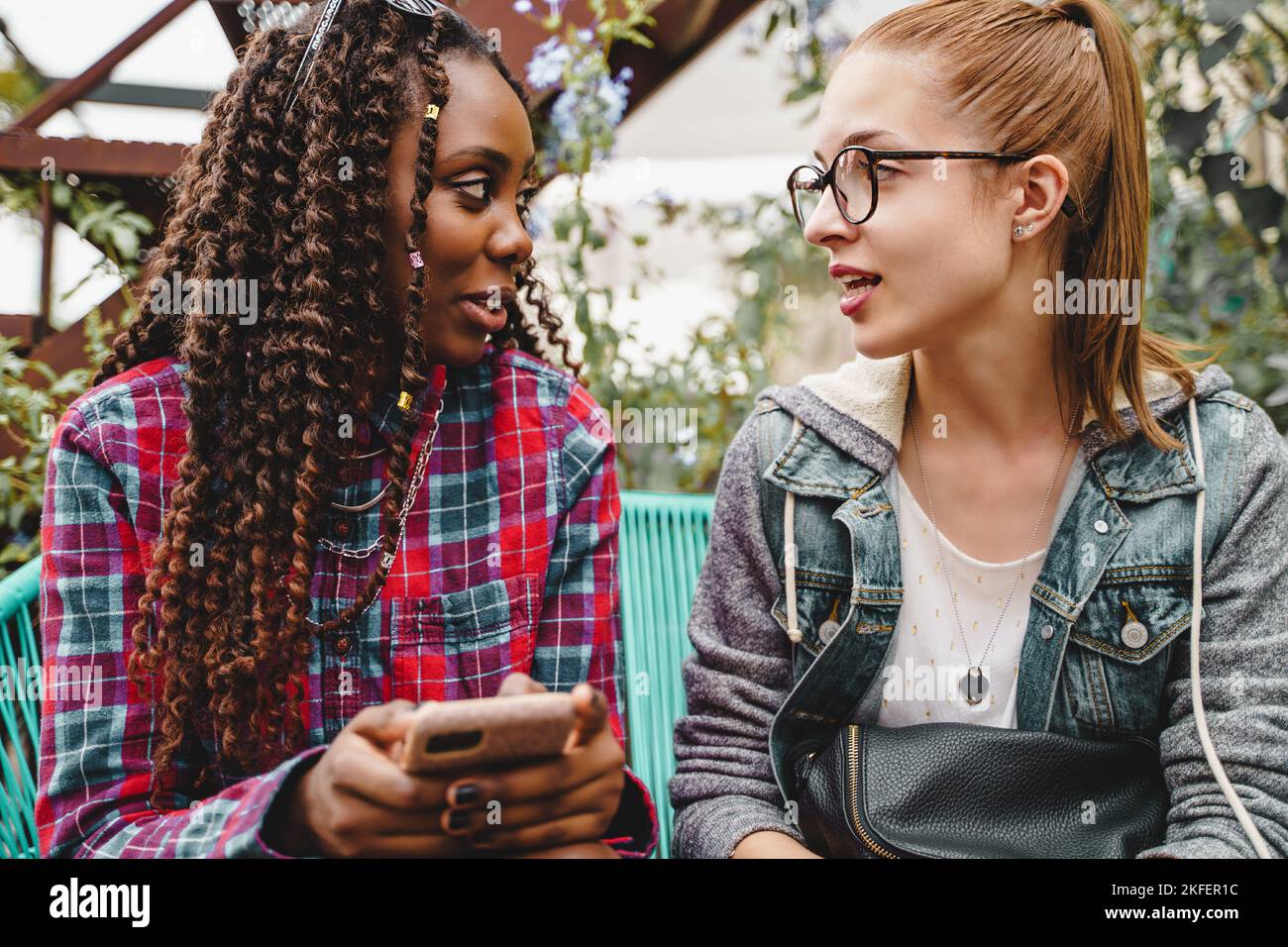 Two young multiethnic women bonding together and talking together ...