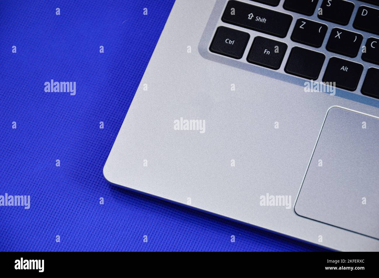 Left view of a white laptop on a blue background Stock Photo - Alamy