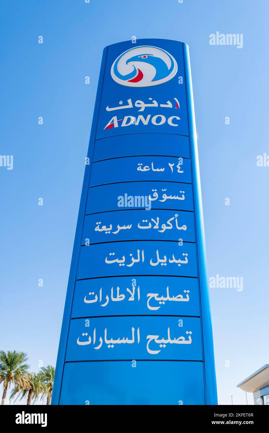 Adnoc Petrol Station blue sign written in arabic against blue sky, a ...