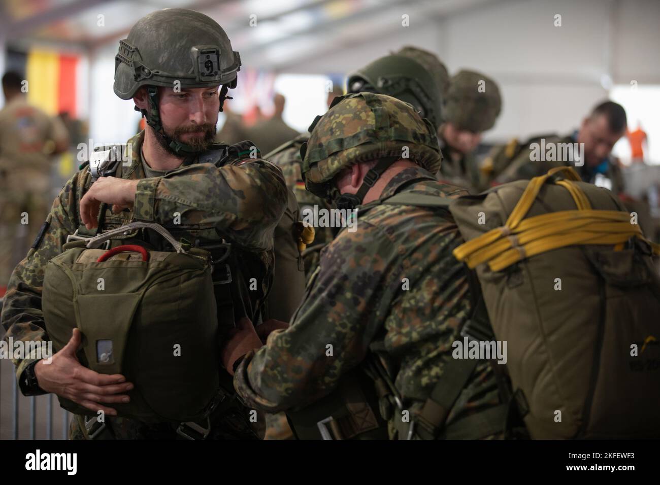 Two German Paratroopers help one another rig up into a French parachute ...