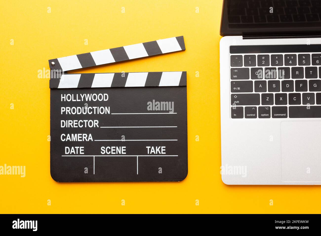 Office stuff with movie clapper, laptop, coffee cup, on yellow table ...