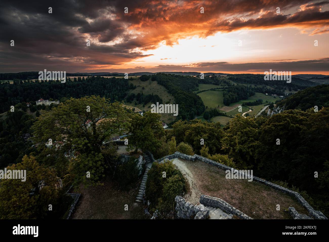 An aerial of a beautiful sunset above an old castle and a green ...