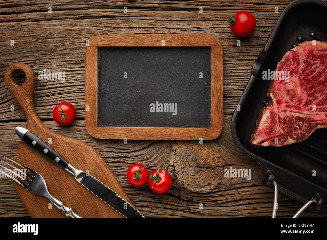 Raw beef steak on the bone with a black frame for inscription. Top view ...