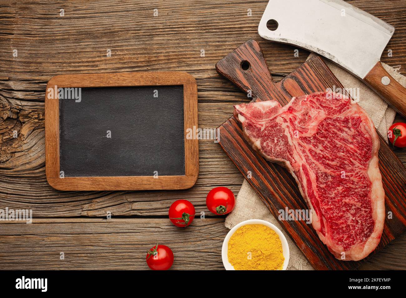 Raw beef steak on the bone with a black frame for inscription. Top view ...