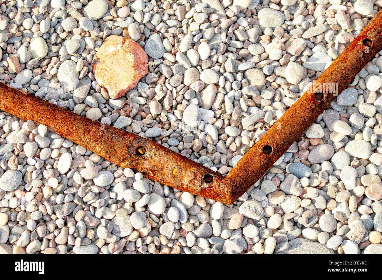 Old rusted textured weathered metal pipe resting on a pebble beach ...