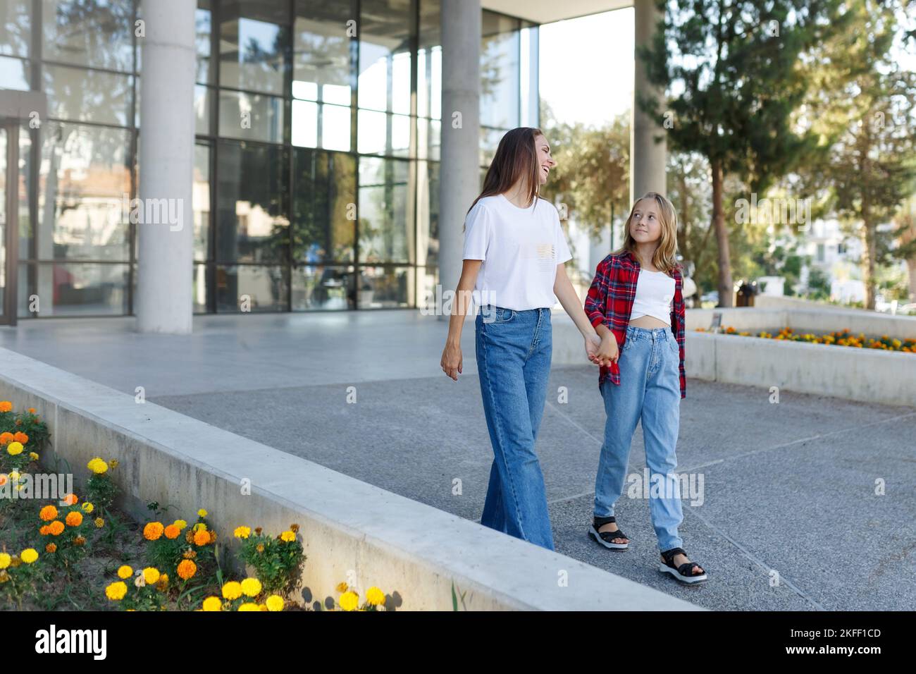 Woman walking and chatting with daughter schoolgirl after school ...