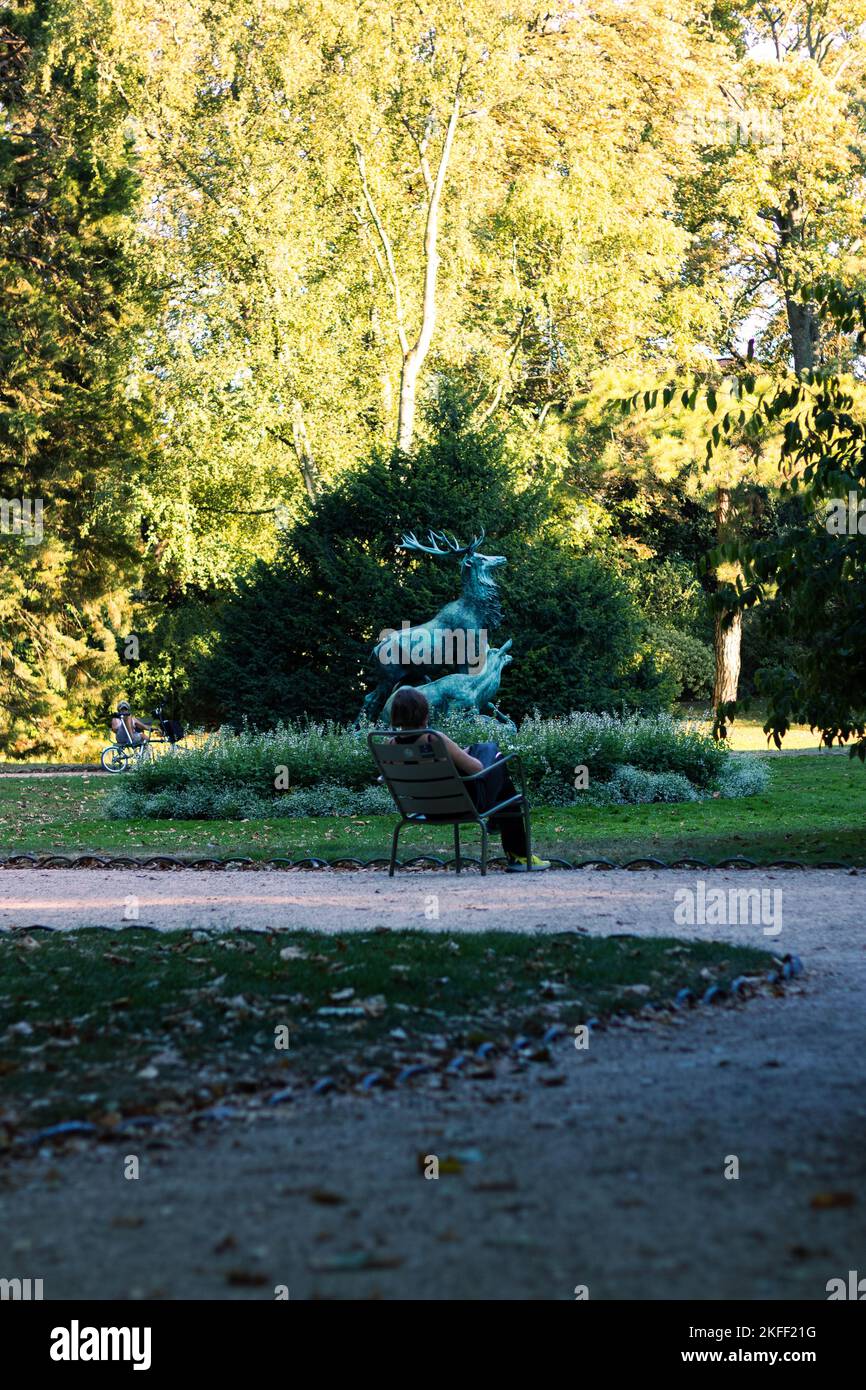 The vertical shot of a woman sitting in front of the statue of Harde de ...