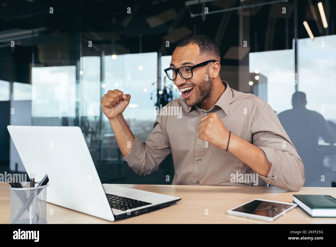 Successful programmer in office with laptop celebrating successful ...