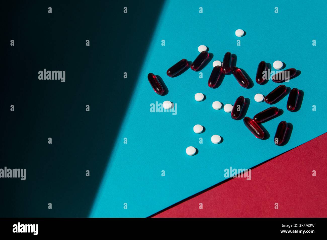 Horizontal photo. Pills with red capsules are scattered on a blue ...