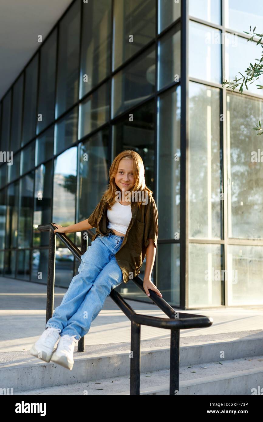 Portrait of teenage girl sitting on stairs, urban street, sunlight ...