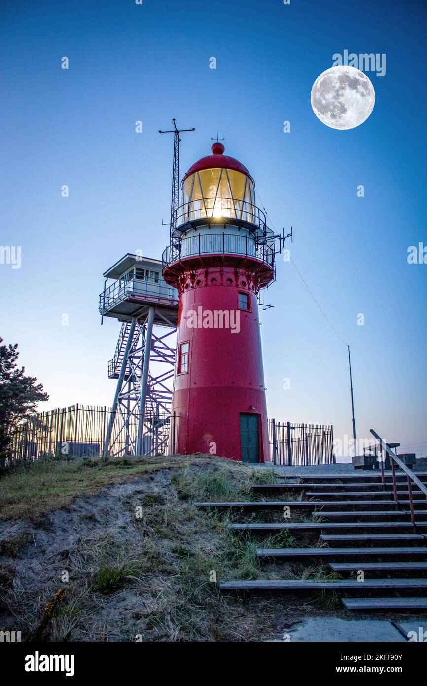 A vertical shot of white full moon in blue sky above the red Vuurduin ...