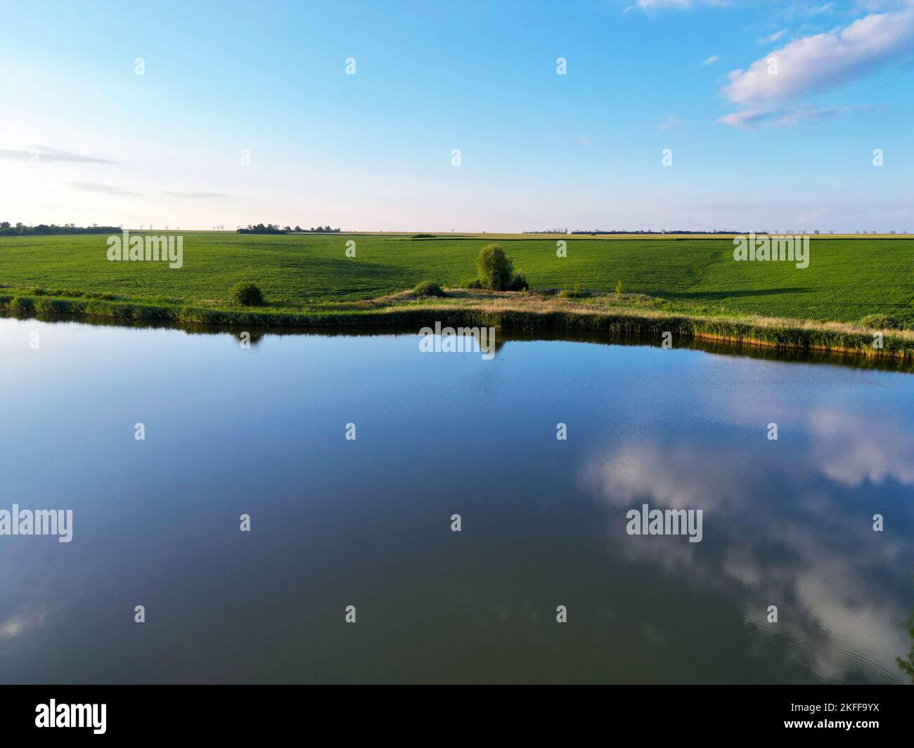 A beautiful view of the lake near the green field and the sky with ...