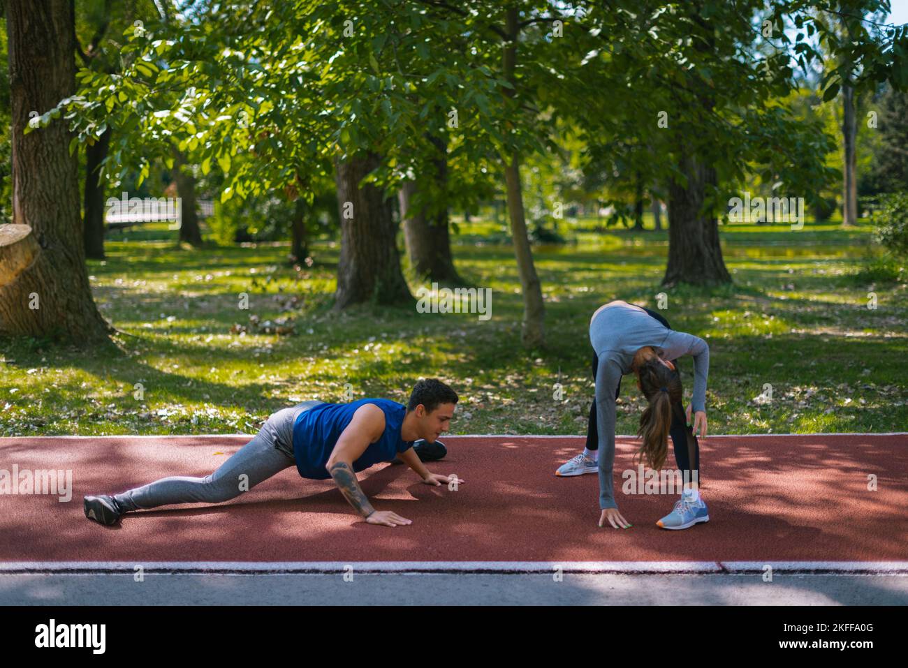 Two young friends exercising together on the runway track at the park ...