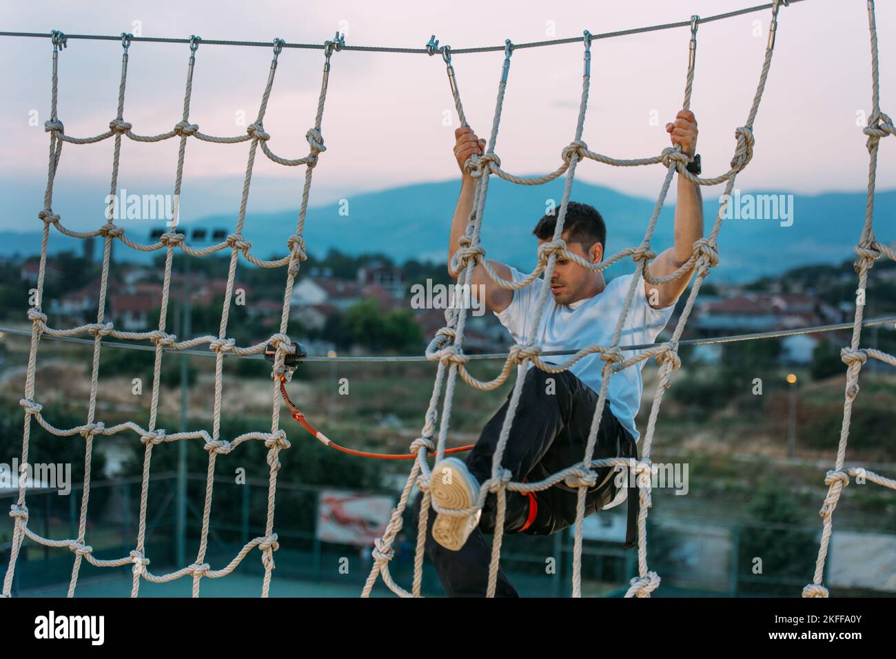 Adventure man climbing the rope at the adventure park Stock Photo - Alamy